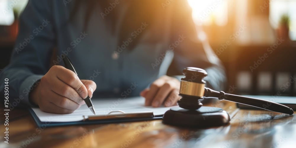 A professional lawyer signing legal documents with a gavel in ...