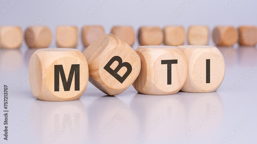 Four wooden blocks spelling 'MBTI' against a light gray backdrop ...