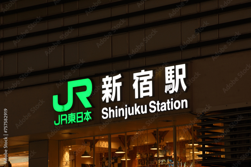 Shinjuku JR train station sign illustrates at night above the ...