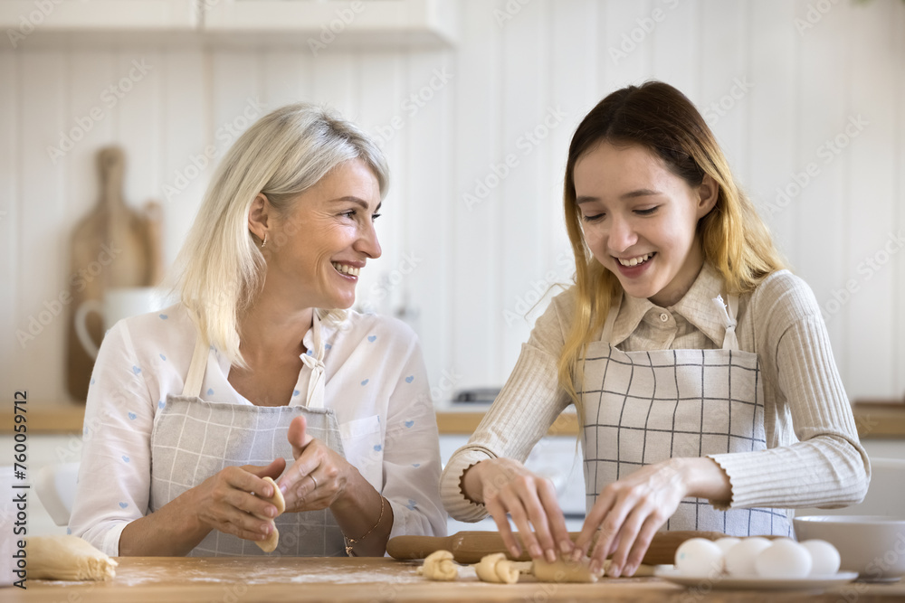 Lovely preteen girl cooking homemade pastries sweets with mother, sit ...