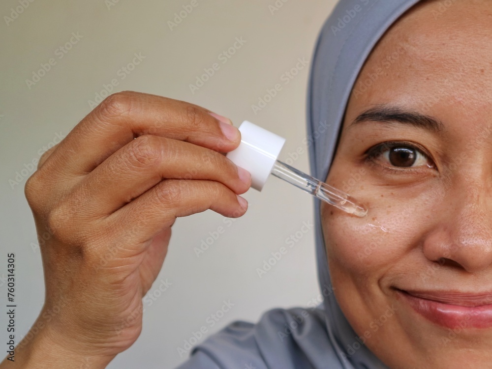 Half face of Happy muslim woman in hijab showing pipette with hydrating ...