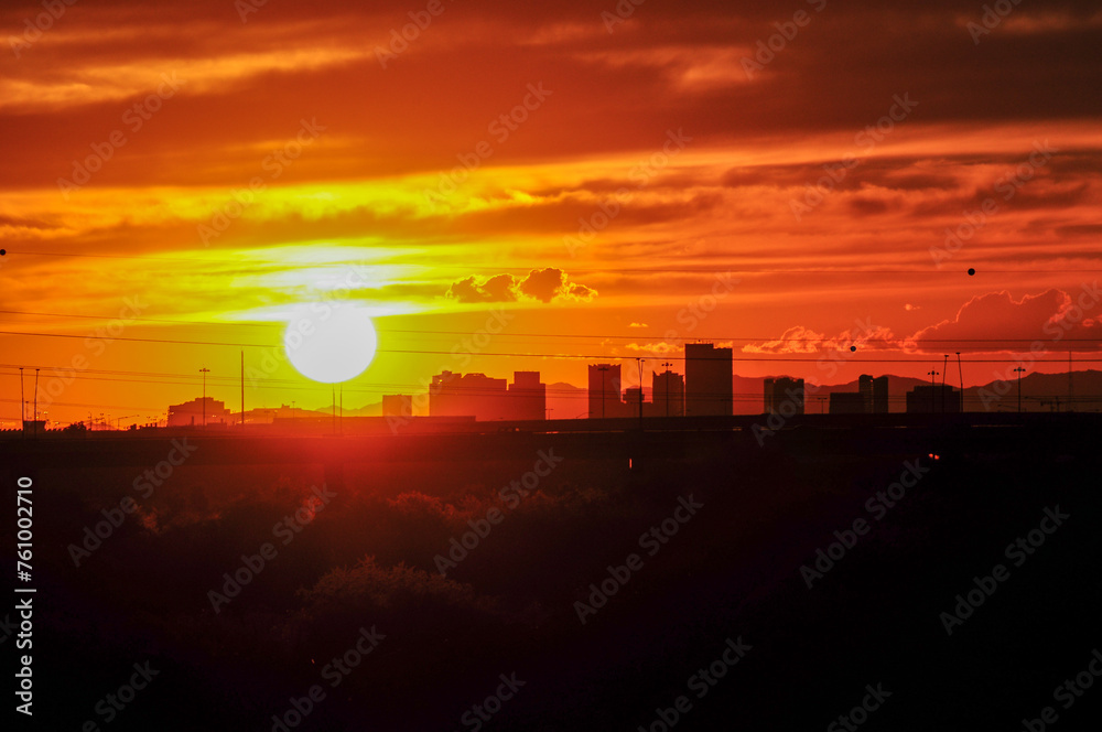 The intense sunlight of a sunset outlines the skyline of downtown ...