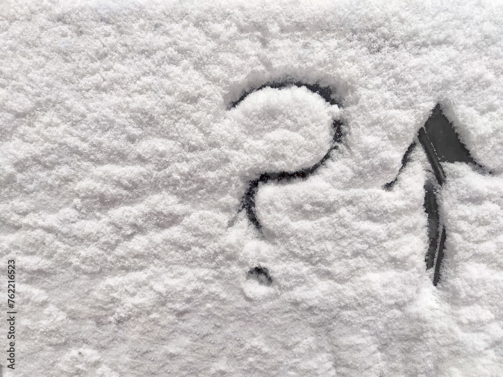 A question mark and arrow written in the snow. The cold frosty texture ...