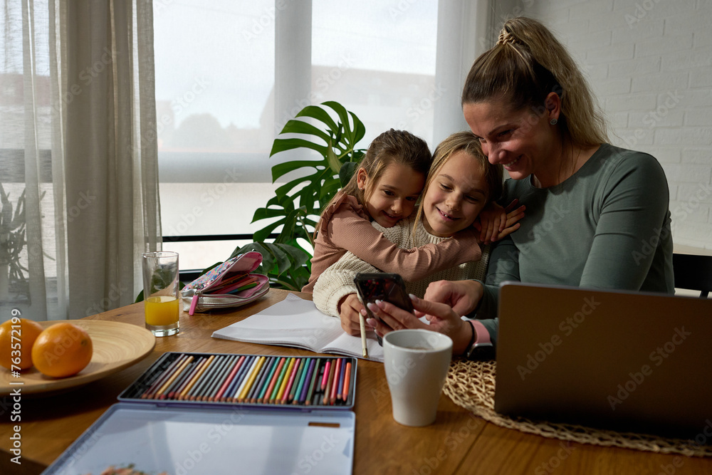 Homework fun: Mother and daughters, seated at the dining table, make ...
