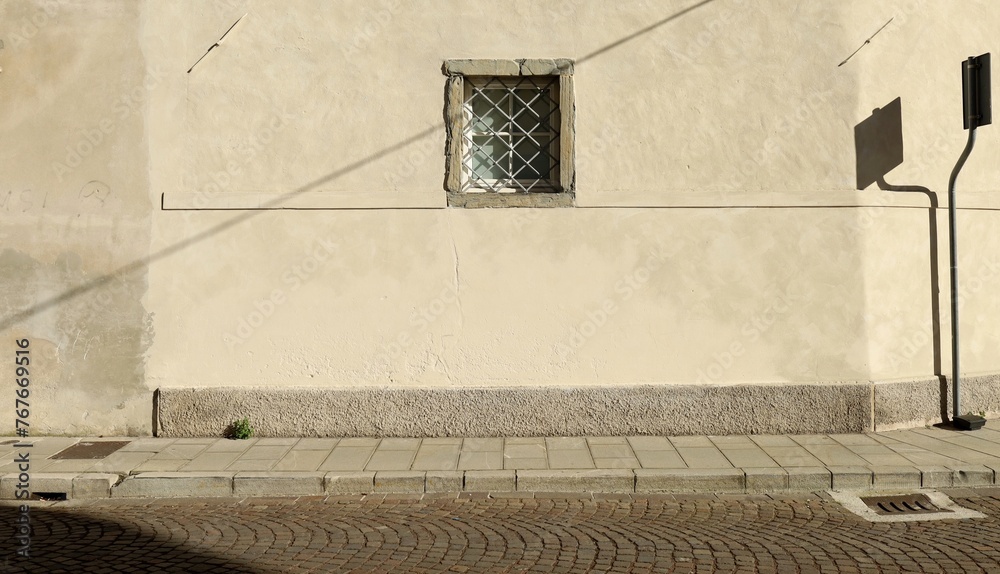 Old barred window on a plaster wall in european city. Stone tiled ...