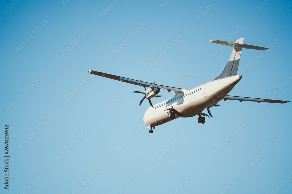 Rear view of an ATR 72 airplane in the clear blue sky. Twin-engine ...