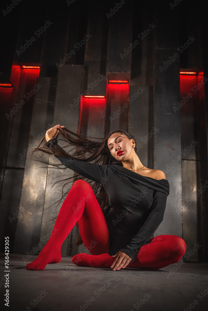 Beautiful young asian girl in black body wear red pantyhose is posing on dark iron wall ...