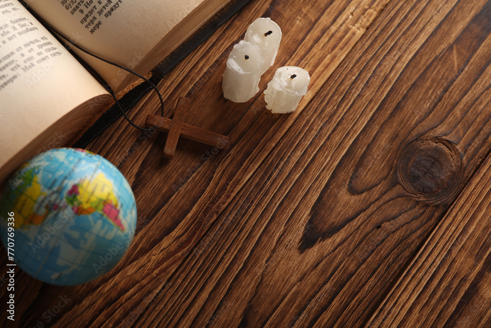 Bible book, candles and wooden Christian cross on a string, globe ...