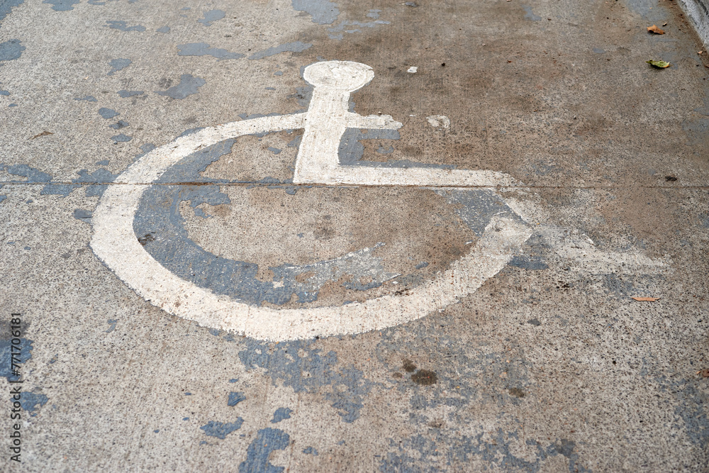 A close-up image capturing a faded and weathered handicap parking sign ...