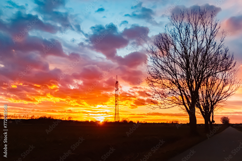 Sunset with a dramatic sky and overland high voltage lines near ...