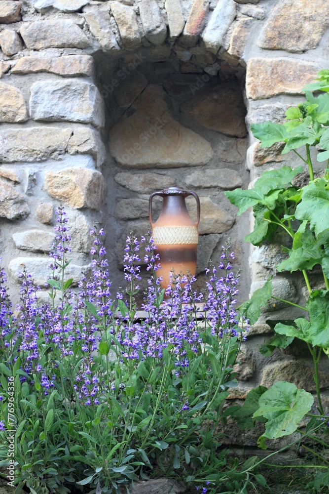 Beautiful niche with amphora in stone wall of the garden. Flowering ...
