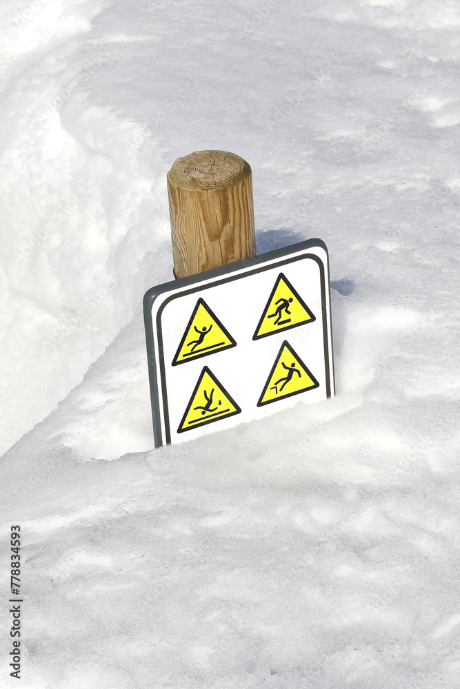 Fresh snow buries a warning sign with pictograms alerting of the danger ...
