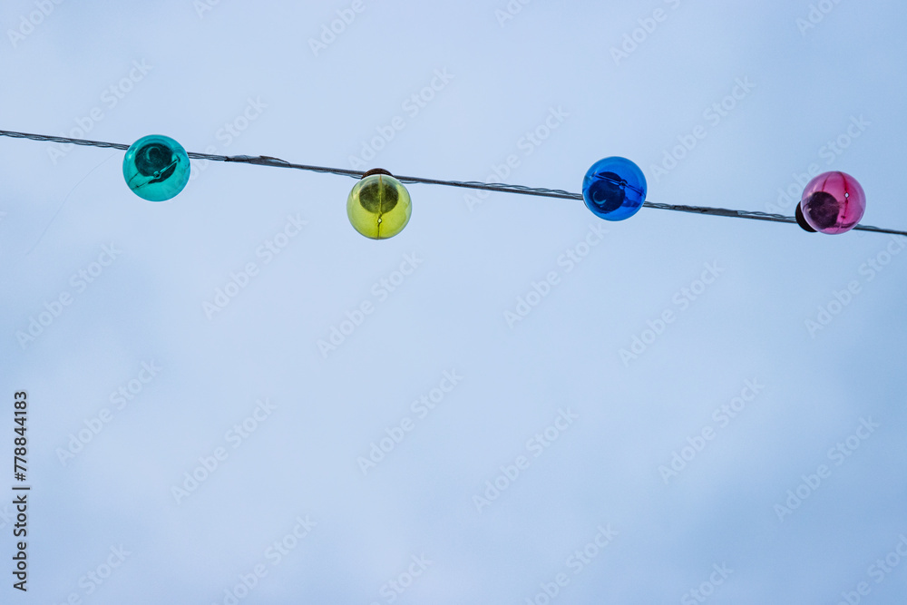 Straight line of Christm garland light bulbs on cloudy sky background ...