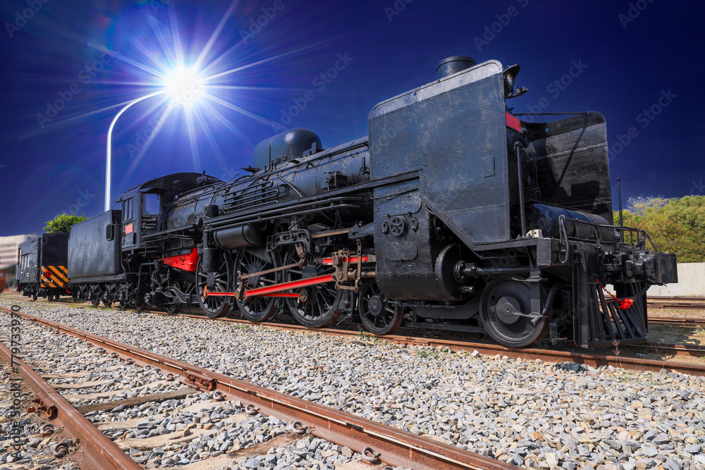 At night, the old steam locomotive is illuminated by modern street ...