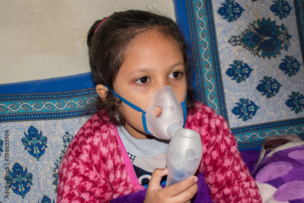 A little girl or child holding a mask nebulizer inhaling medication ...