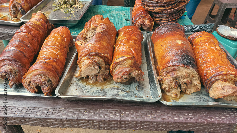 Rows of golden brown roasted pork belly or lechon liempo displayed at a ...