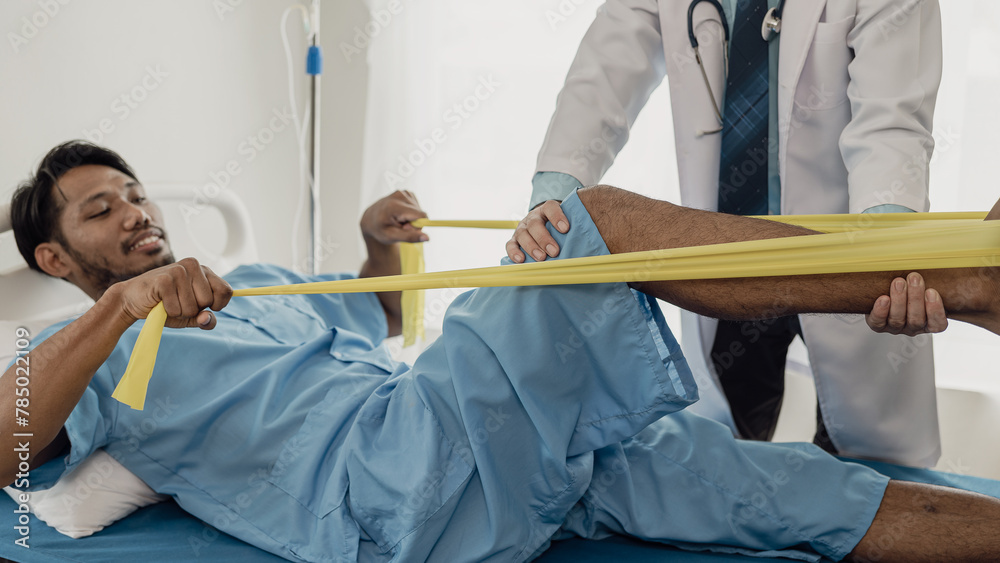 Physical therapist helping a patient while stretching his legs on a bed ...