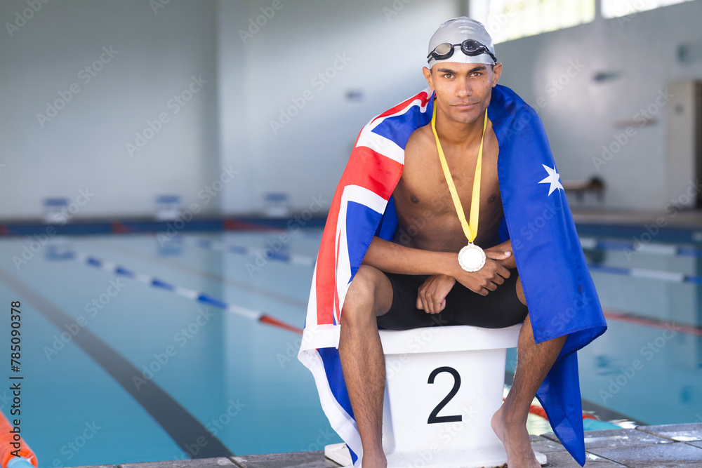 Male athlete swimmer wrapped in Australian flag sitting on podium with ...