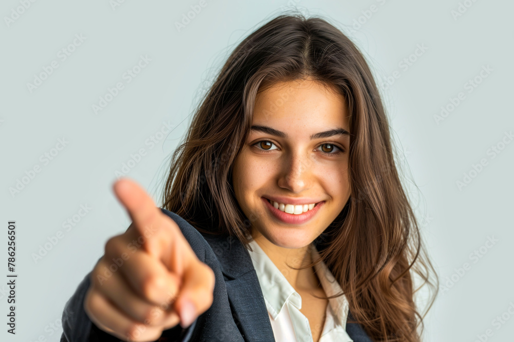 Young smiling woman pointing finger at viewer on light blue background ...