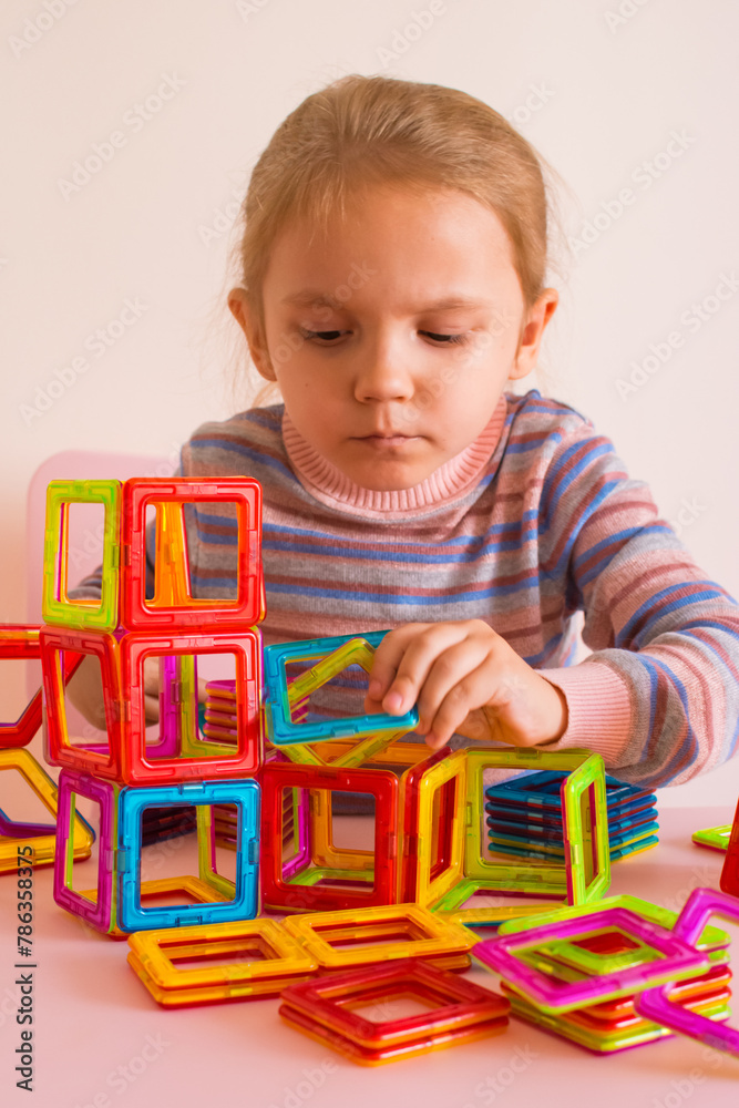 The child assembles a magnetic construction set, builds houses, towers, cars. Educational games ...