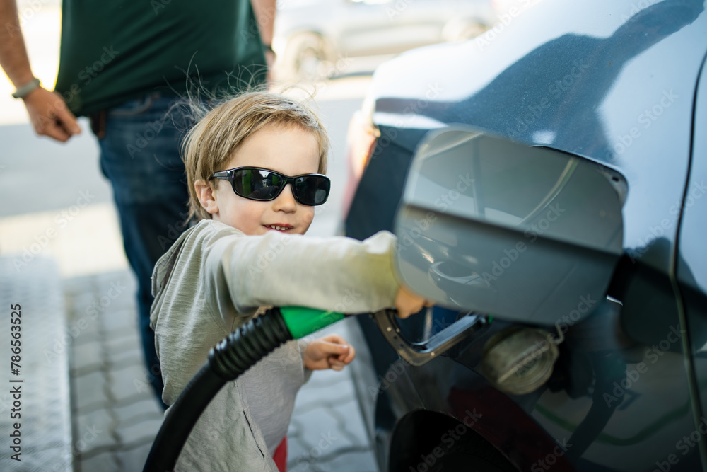 Cute little blond boy holding pump nozzle. Small kid helping father to ...