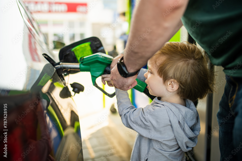 Cute little blond boy holding pump nozzle. Small kid helping father to ...