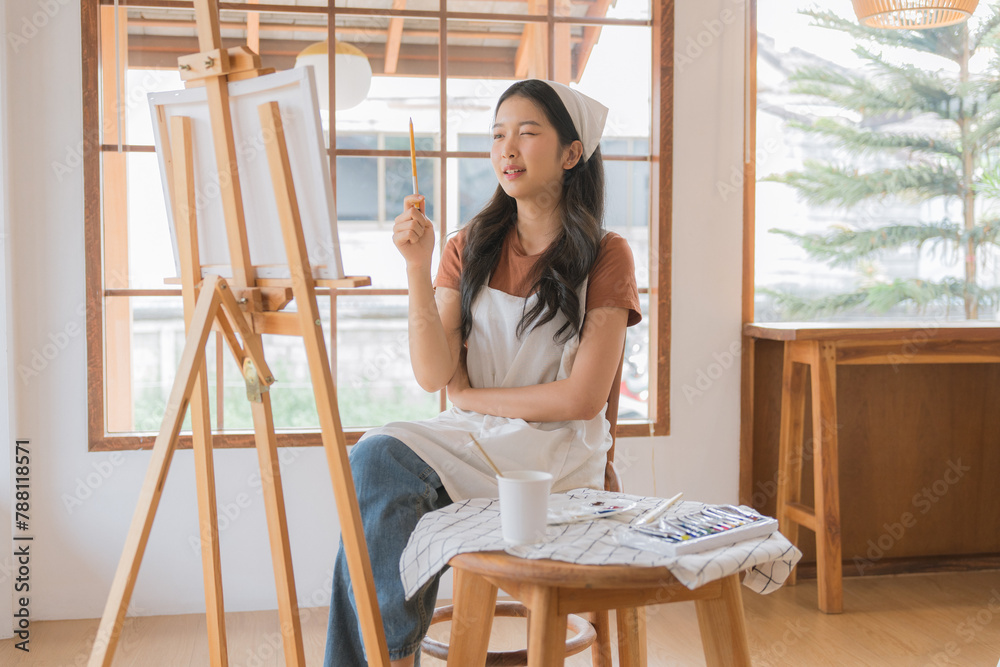 Asian young talented woman artist coloring on painting board in house ...