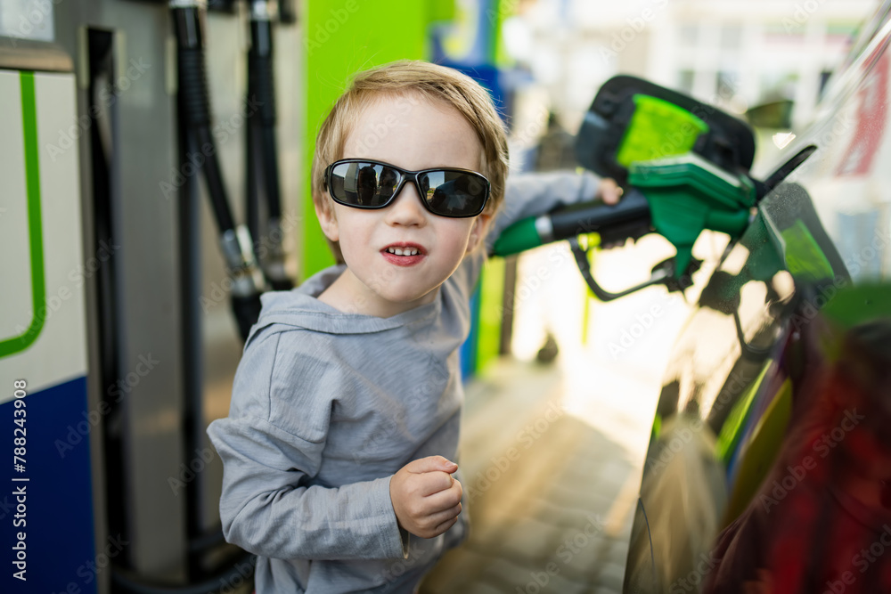 Cute little blond boy holding pump nozzle. Small kid helping father to ...
