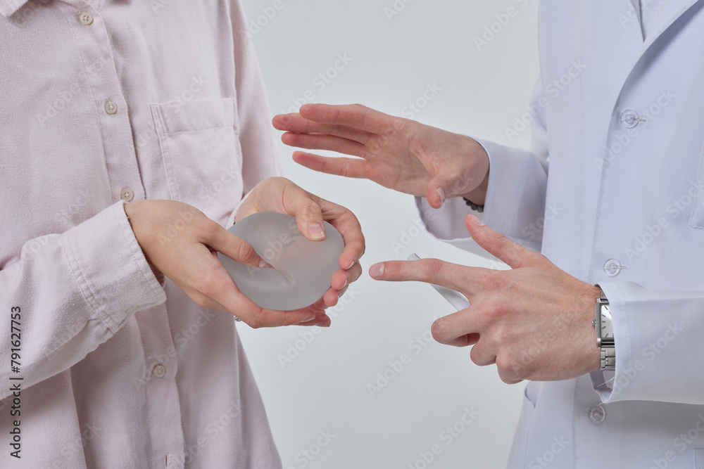 Professional plastic surgeon showing silicone breast implants to his ...