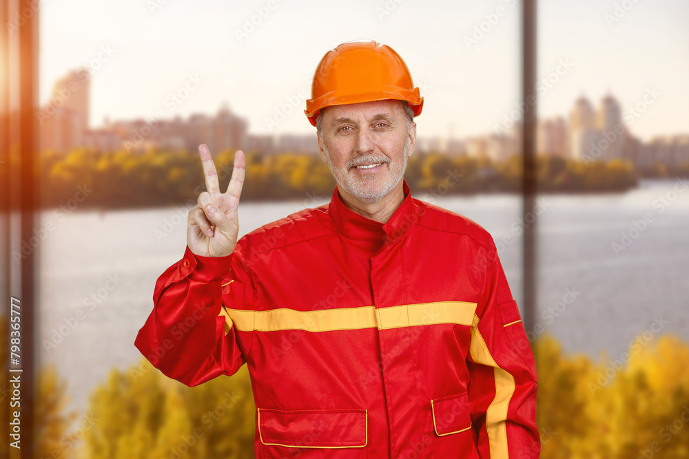 Happy smiling construction worker shows victory gesture sign. Window ...