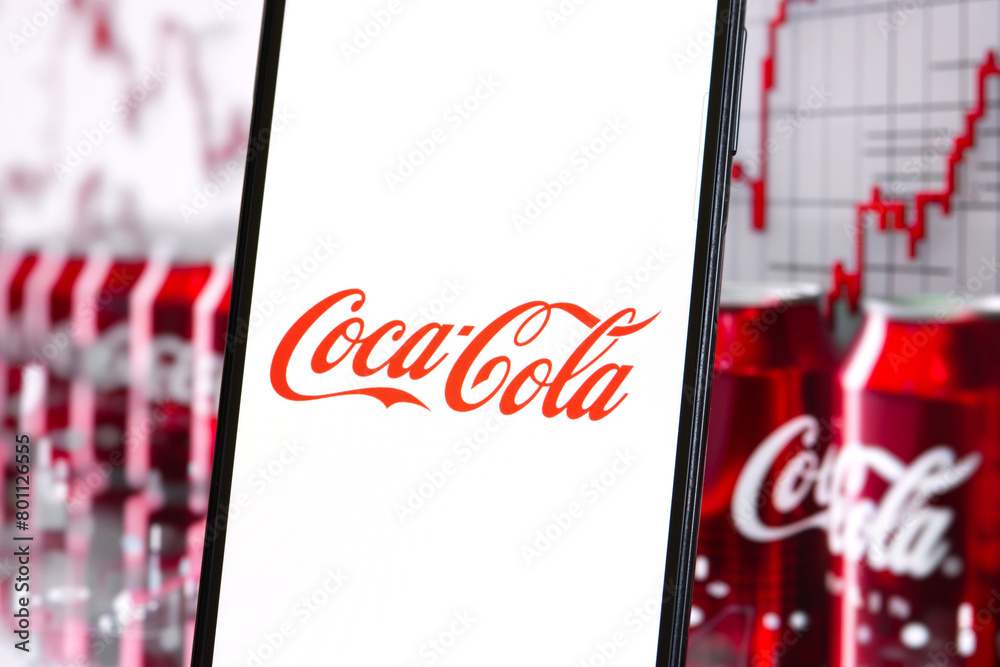 Coca-Cola company logo on screen of smartphone against blurred background of Coca-Cola drinks ...