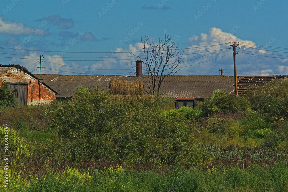 Dying Russian village. a tractor transports bales of hay, moving along ...
