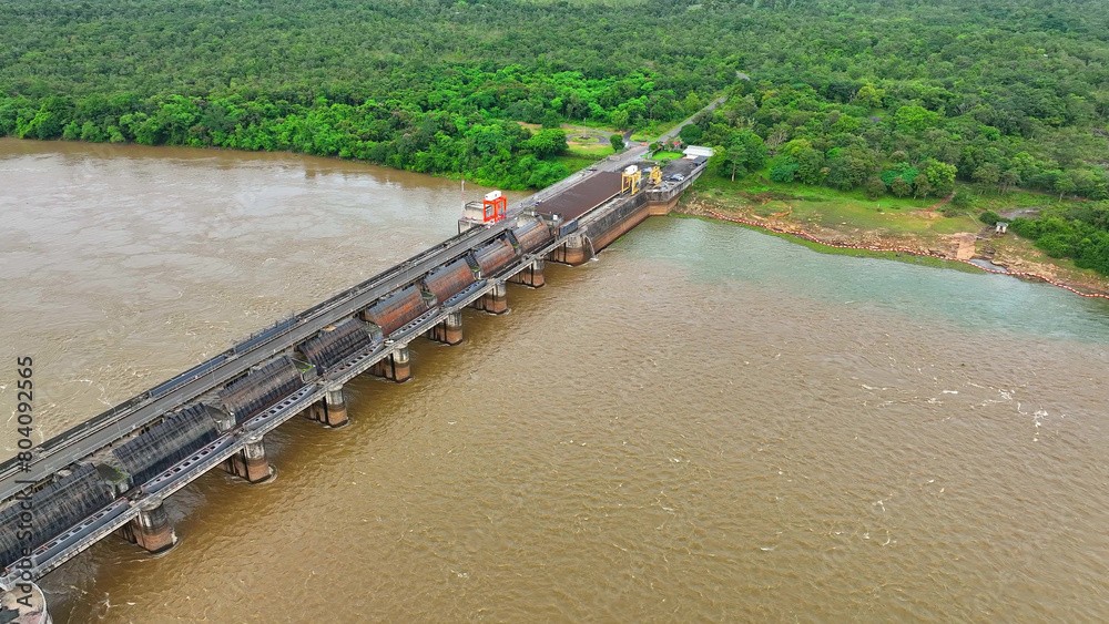 The formidable dam reigns over the swollen river, its sturdy floodgates ...