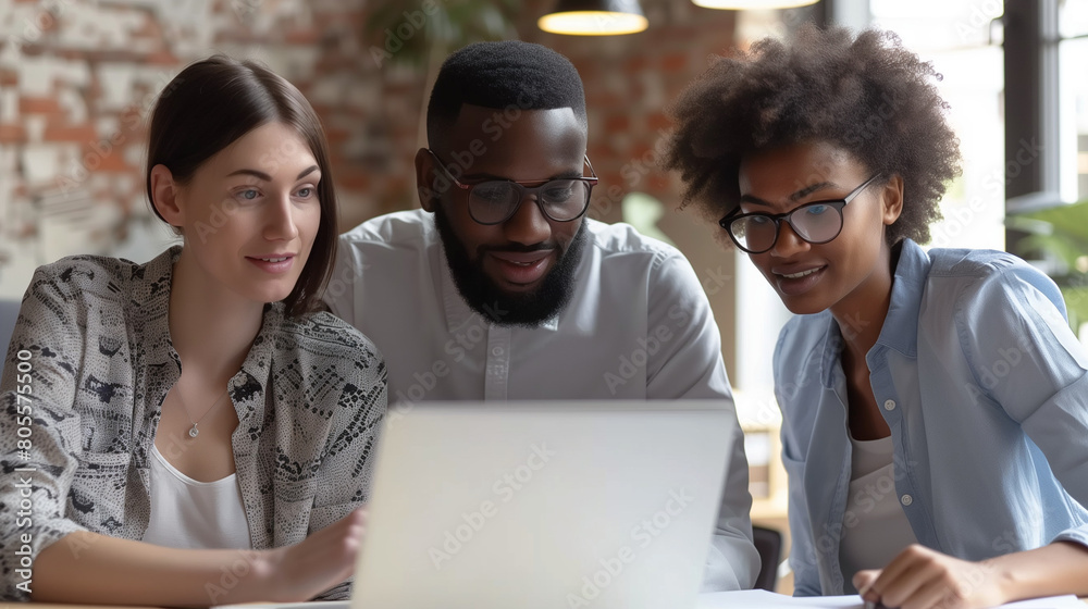 Focused multiracial colleagues sit at desk in office look at laptop ...