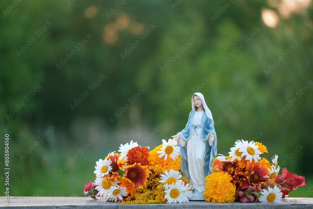 Figurine of Our lady, grace virgin Mary with flowers outdoor, natural ...