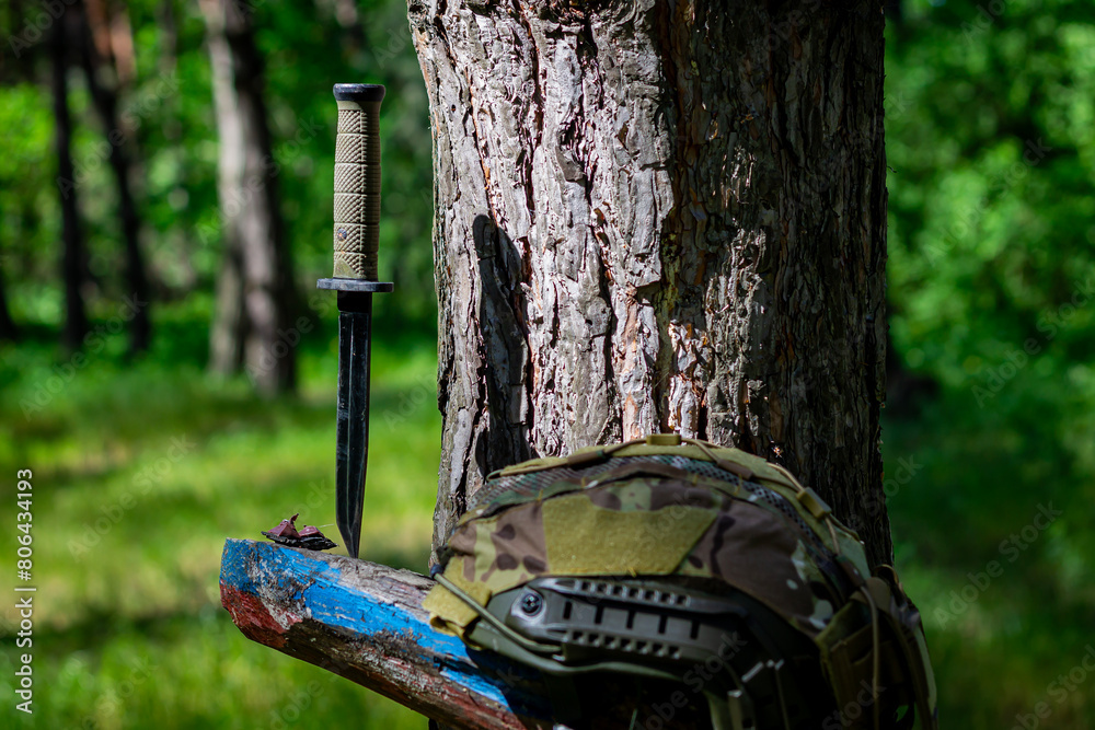 Military assault helmet and tactical knife in the forest on a tree ...