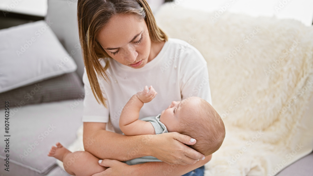At home, joyous mother sitting on sofa, confident, lovingly trying to ...