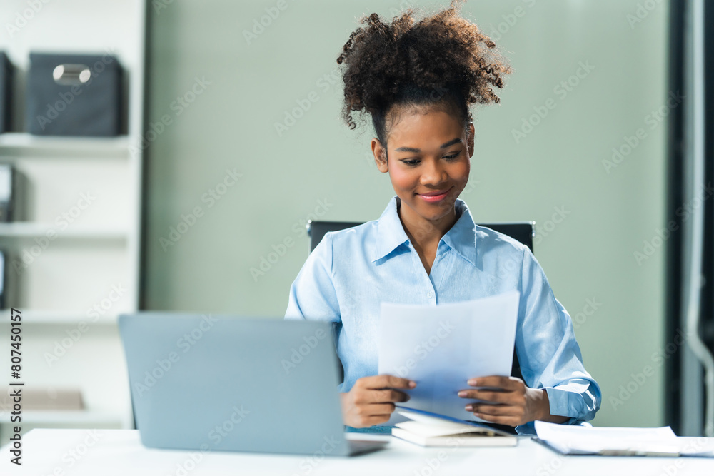 Analyzing business charts A4, a young African American woman in a blue ...