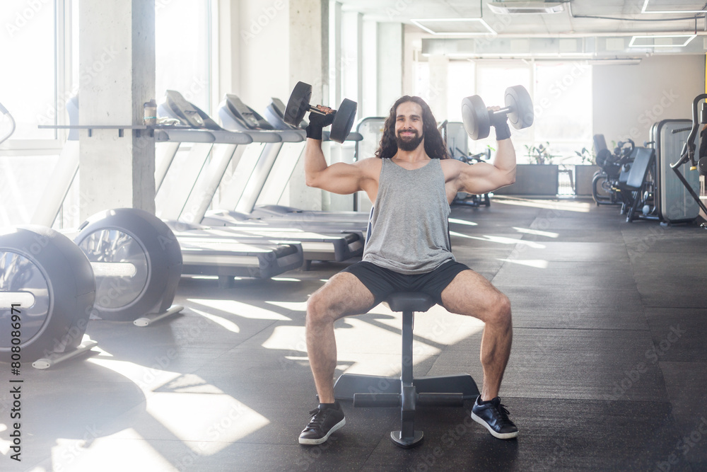 Portrait of confident strong man with long curly hair athlete working ...
