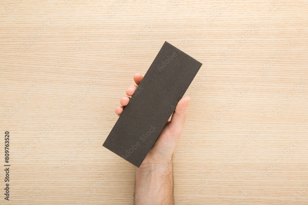 Young adult man hand holding and showing new dark black sandpaper ...