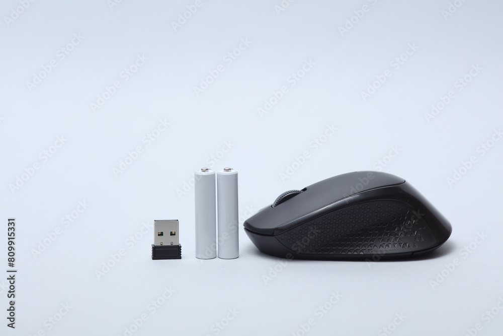 Wireless PC mouse with USB flash drive and batteries on a white ...
