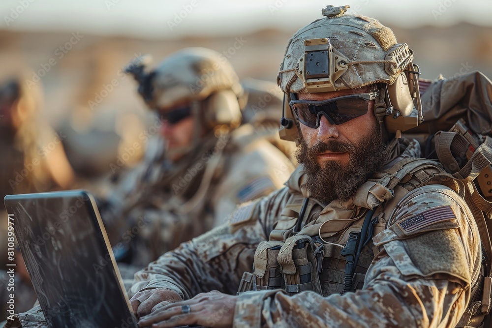 Two soldiers in full gear attentively using a laptop, showcasing ...