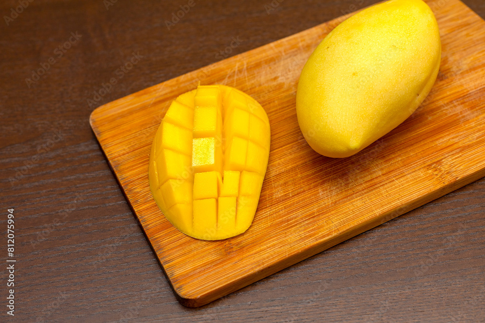Mango. Close up of fresh ripe mango fruit with leaves over dark wooden ...