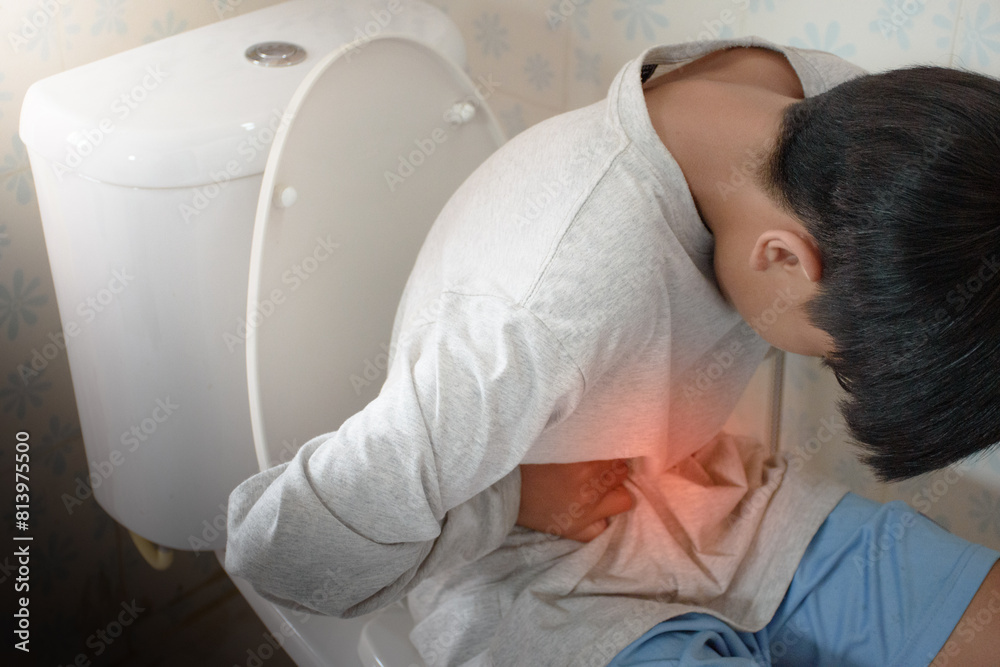 Asian boy sitting on toilet and holding his stomach with stomach pain ...