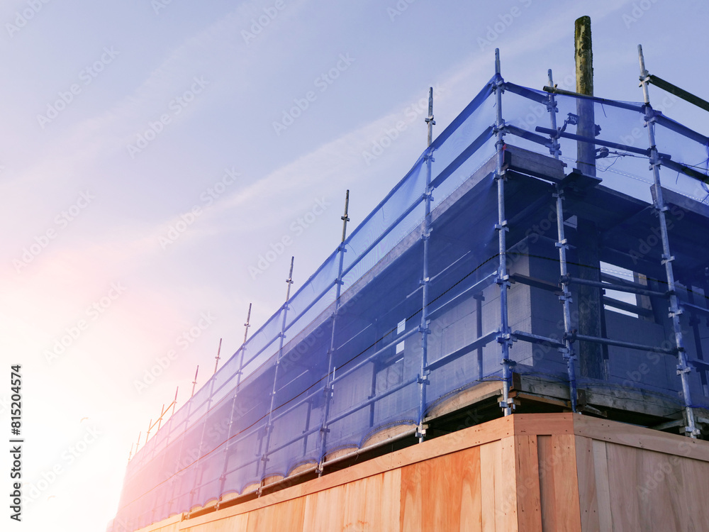 Construction area with ply wood safety fence and scaffolding covered in ...