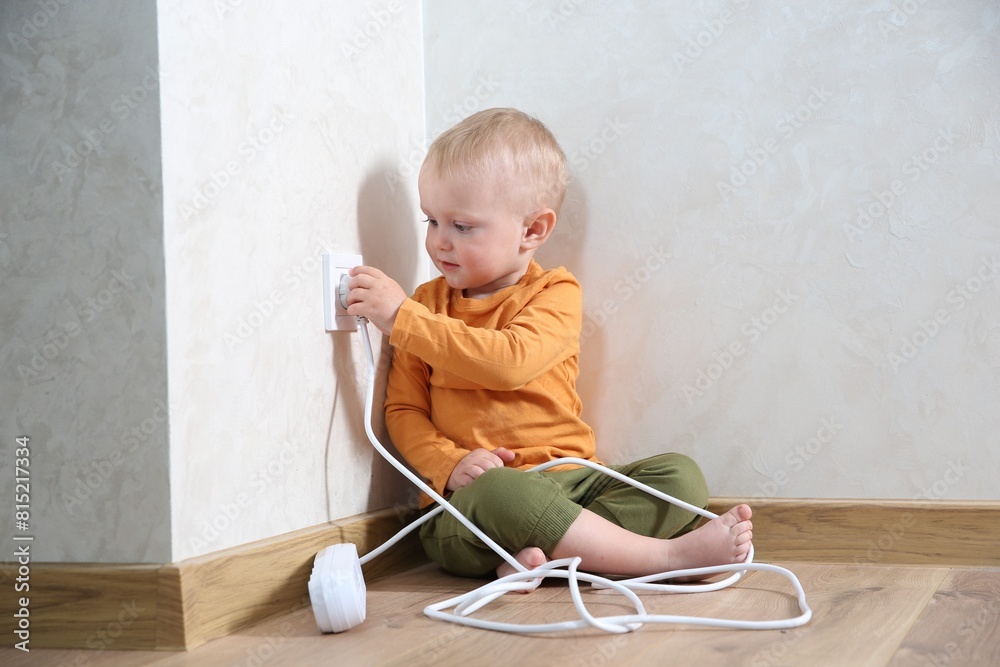 Little child playing with electrical socket and power strip plug at ...