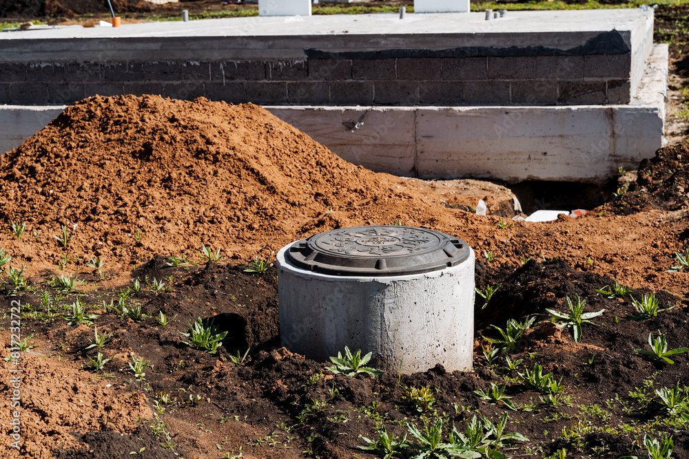 Construction in progress at site with concrete manhole cover and soil ...