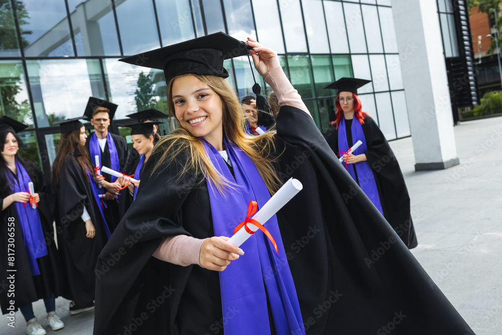 Portrait of graduate student standing in front of her friends with toga ...