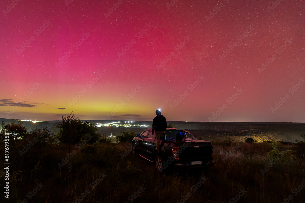 man standing on pickup wheel and watching bright rose green purple ...