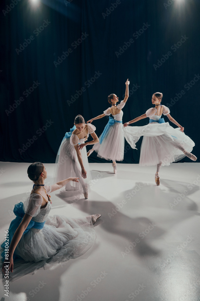 Four ballet dancers in flowing white costumes with blue ribbons ...